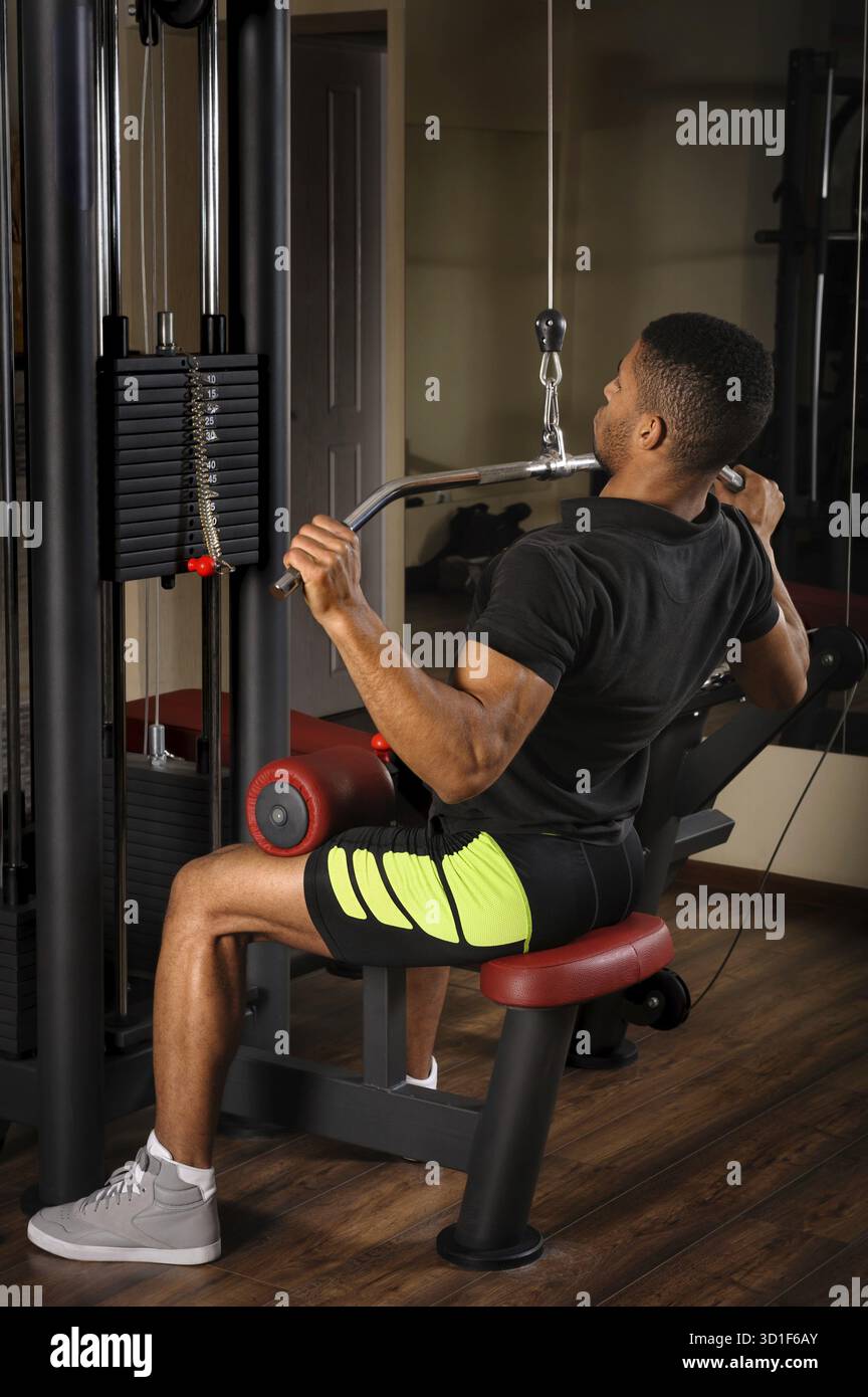 Handsome young african descent Mixed-race man doing lats pull-down ...
