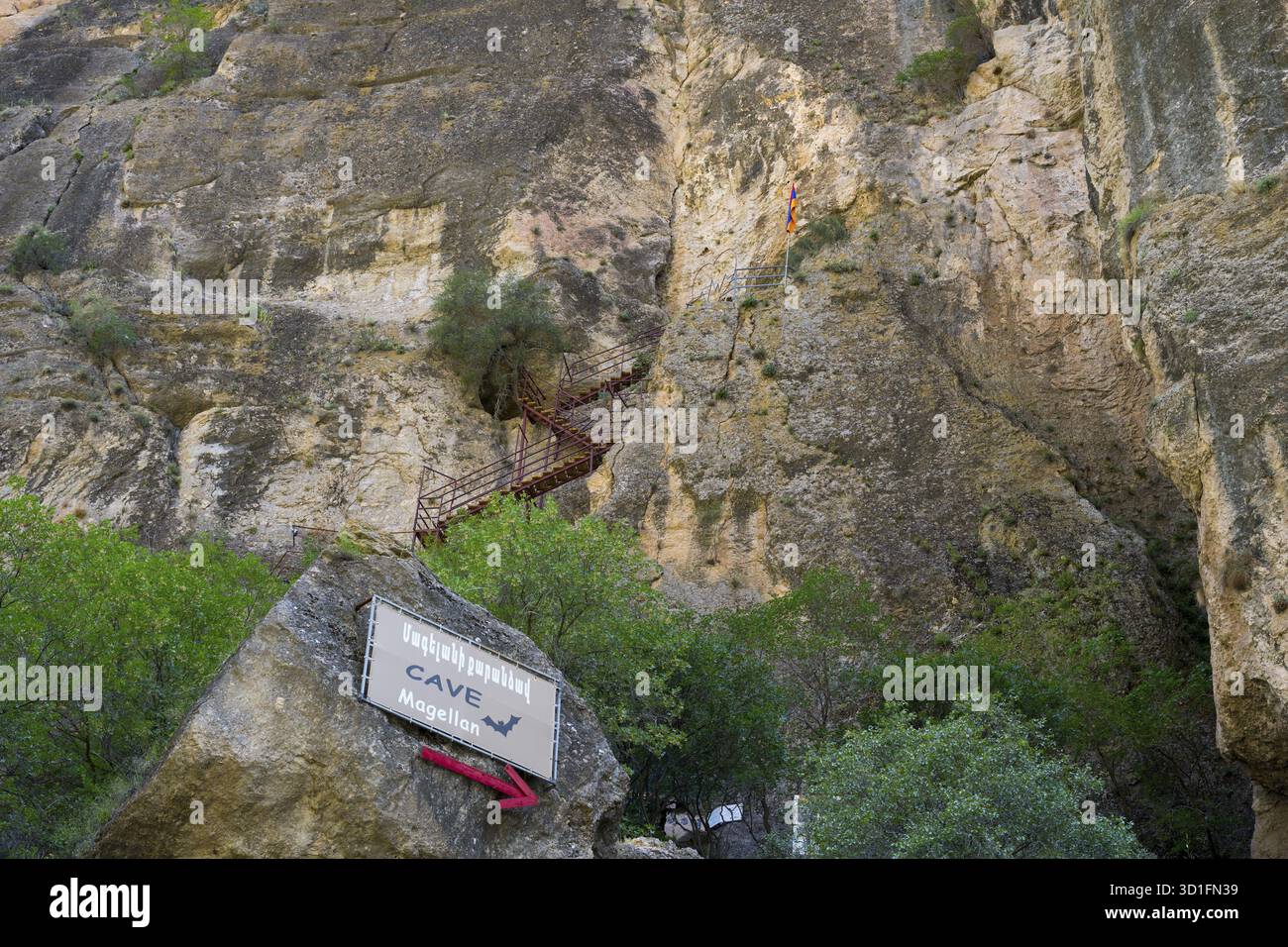 Steep rock wall with a cave and a signpost, Amaghu Gorge, rock wall has ...