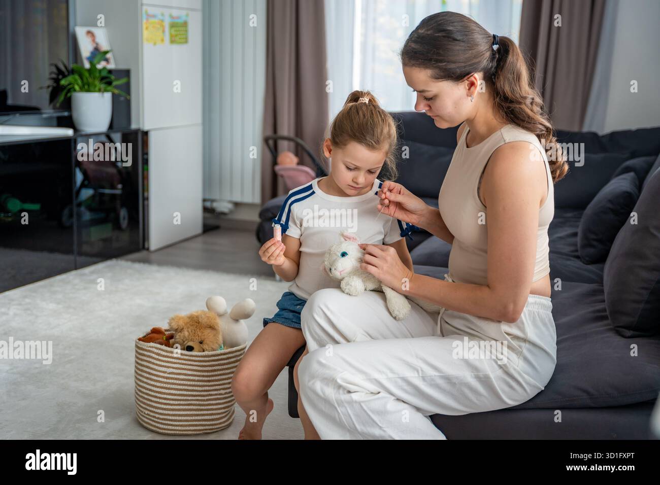 Mother fixing her daughter favorite toy while the girl helps. Warm ...