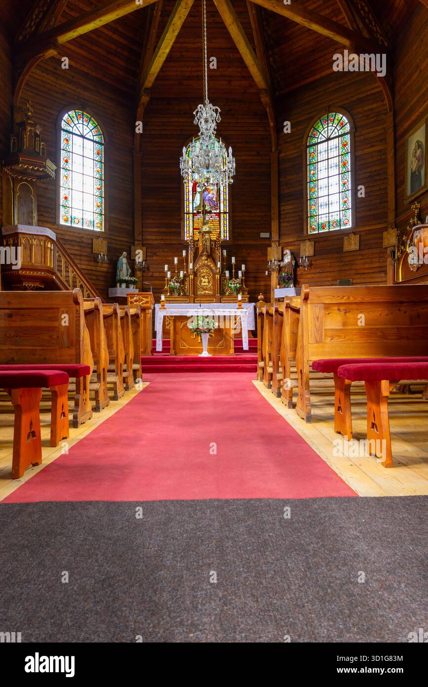 Interior of a traditional wooden church with altar, pews, stained glass ...