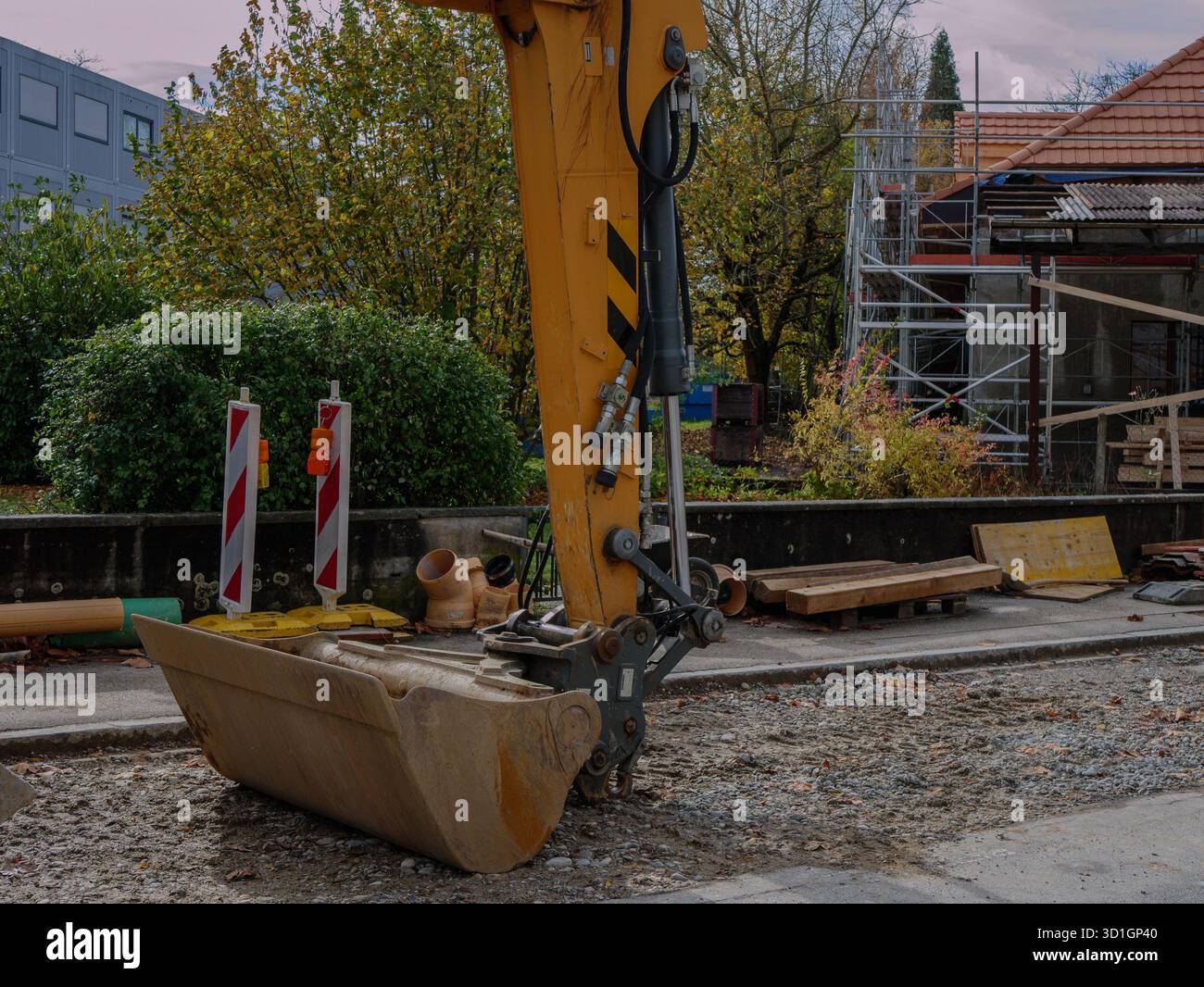 Excavator bucket on urban road construction site with red and white ...
