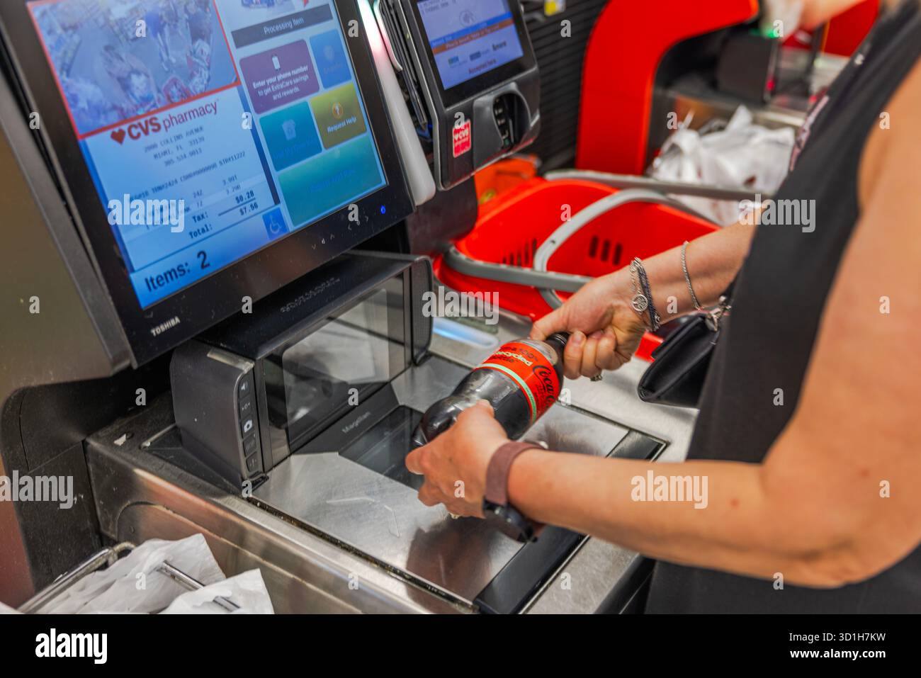 Close up view of woman scanning Coca Cola bottle at CVC self checkout ...