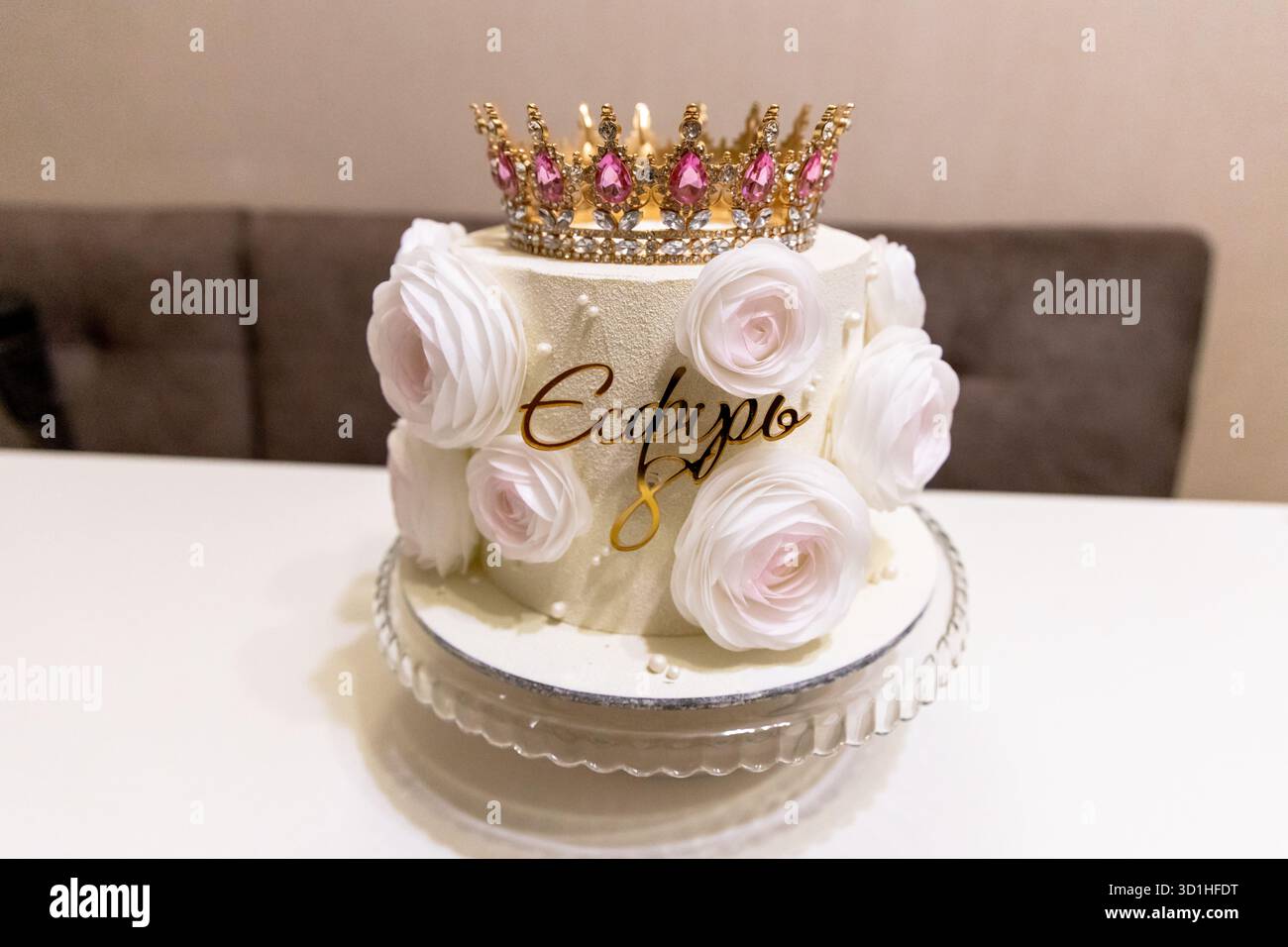 Elegant white cake adorned with roses and a sparkling crown, perfect ...