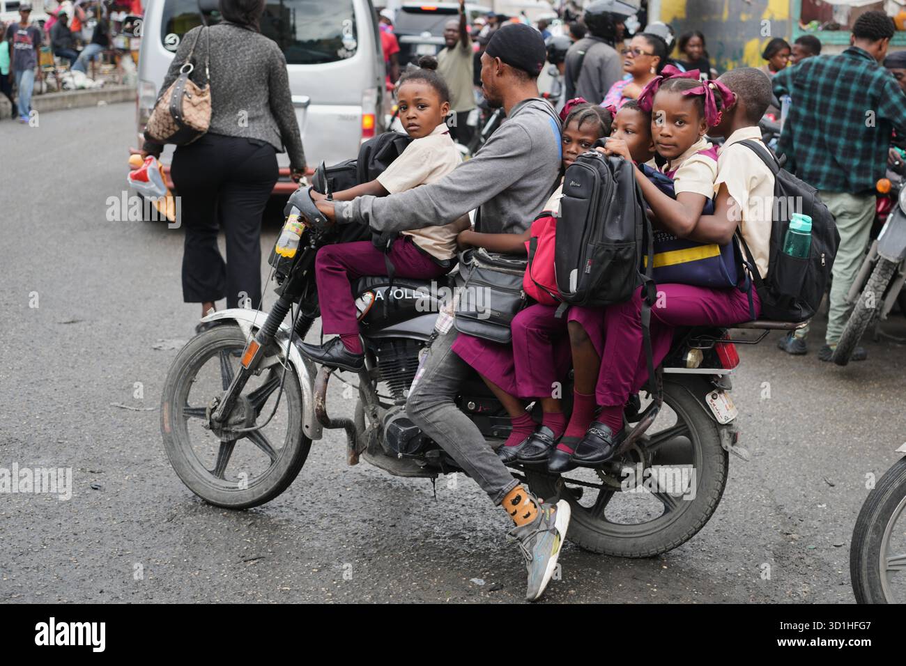 A motorcycle taxi driver transports students after school in Port-au ...