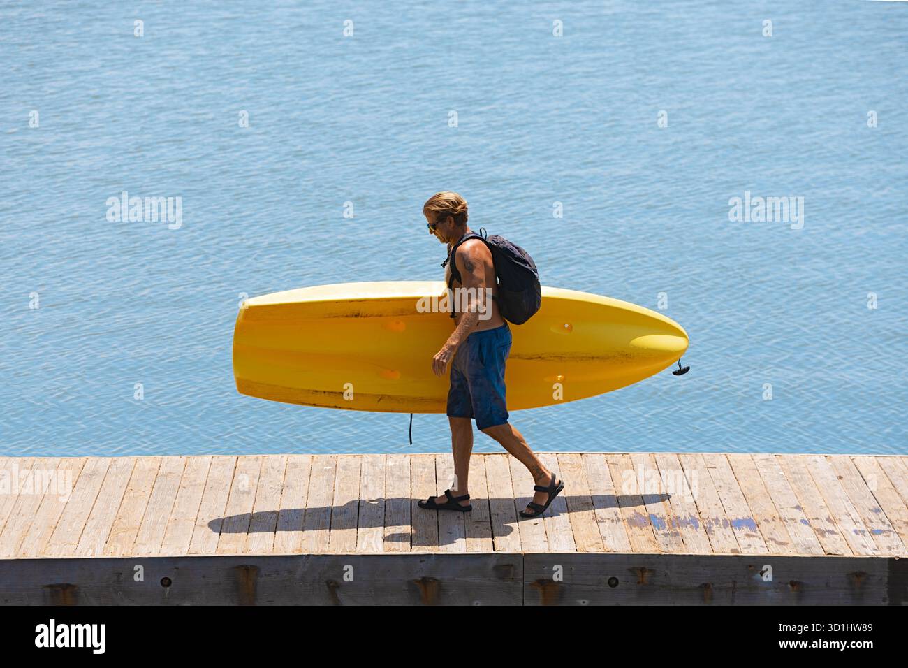 Person carrying a stand-up paddle board, also known as a SUP Stock ...