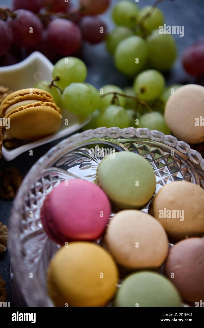 A vertical close up captures colorful macarons in a glass bowl with ...