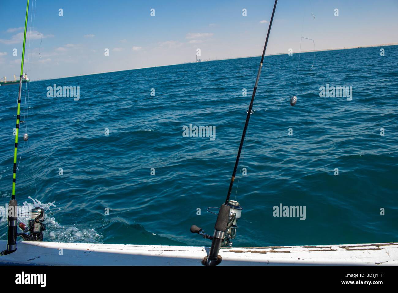 Two fishing rods one green and one black are trolling from the back of ...