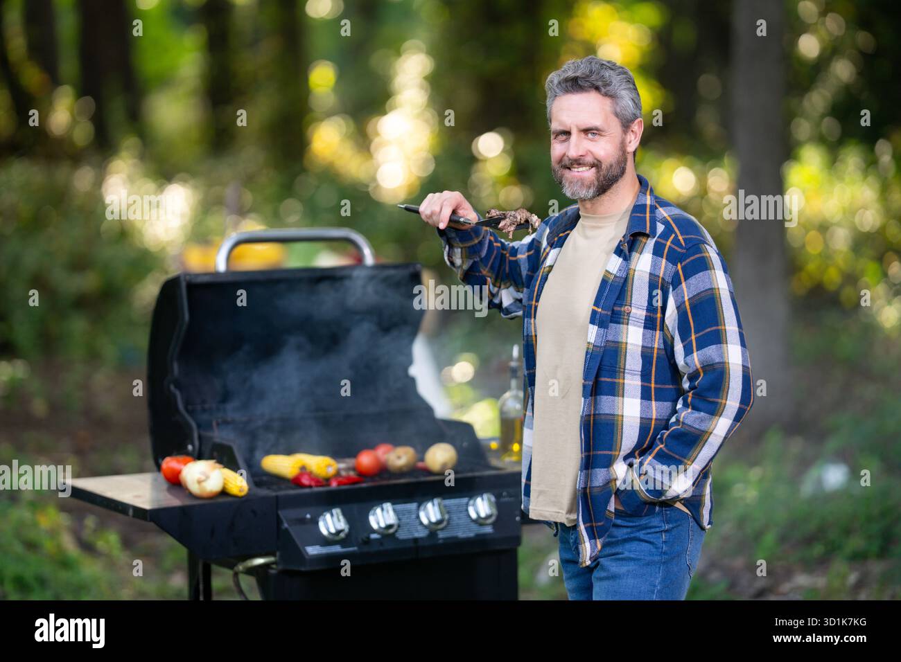Man grilling steak on a backyard barbecue. Chef 40s cooking gourmet ...