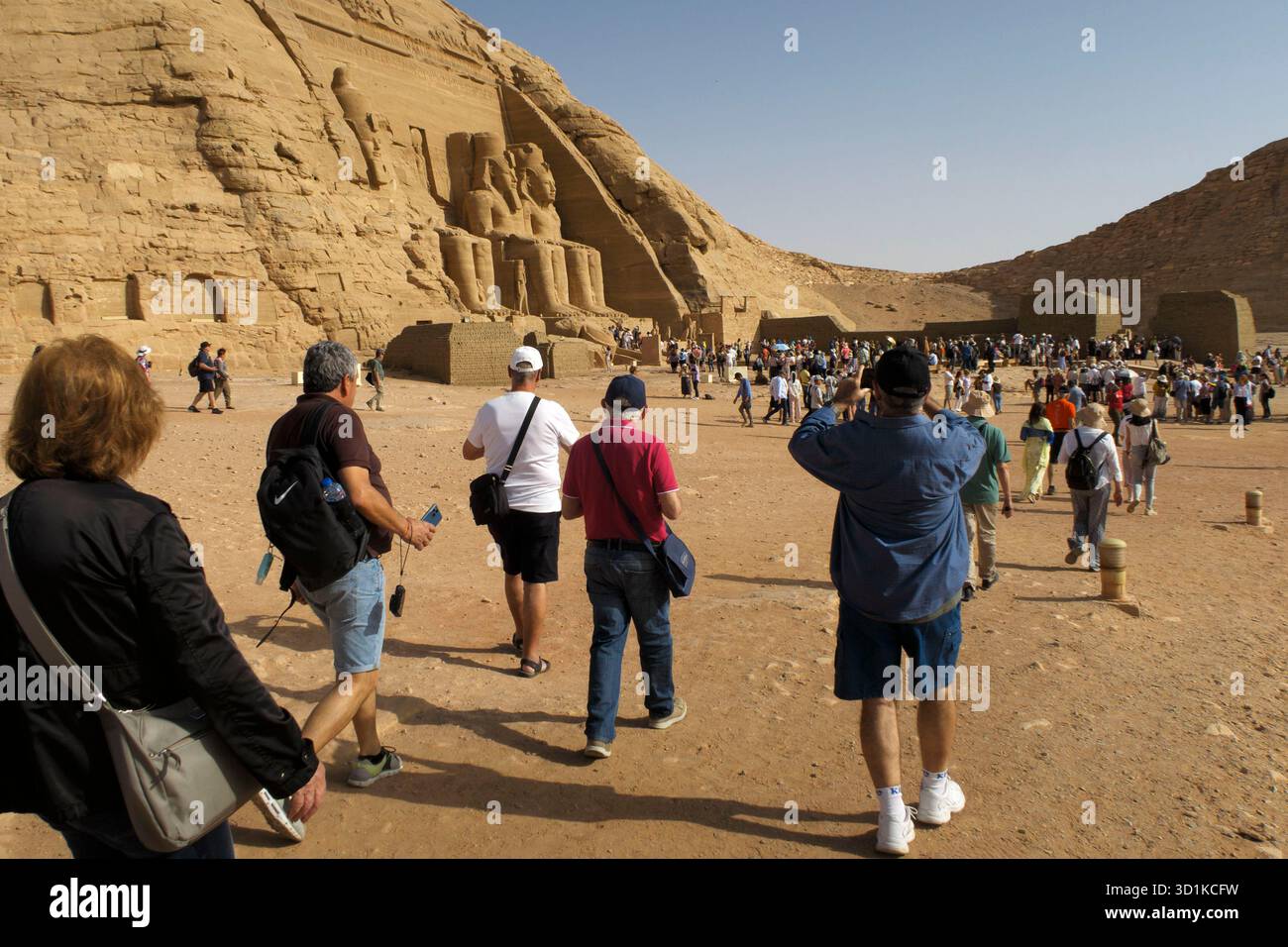 Tourists visiting the ancient rock-cut Abu Simbel temples in the desert ...