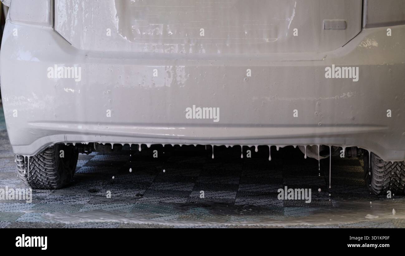Rear part of a car being cleaned at a professional car wash, fully ...