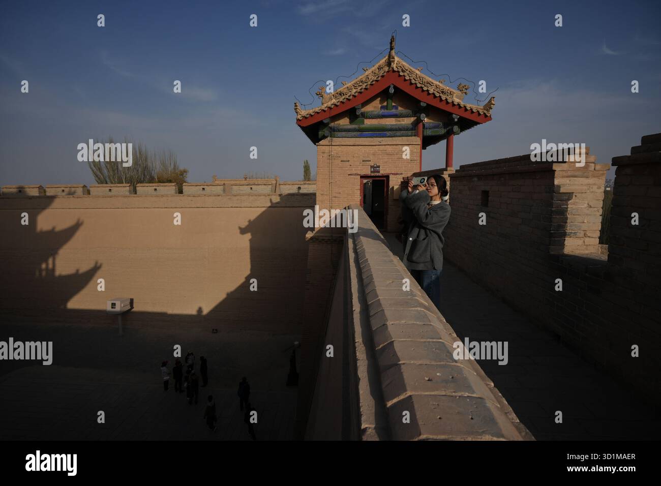 A woman takes a smartphone photo as visitors tour Jiayu Pass point of ...