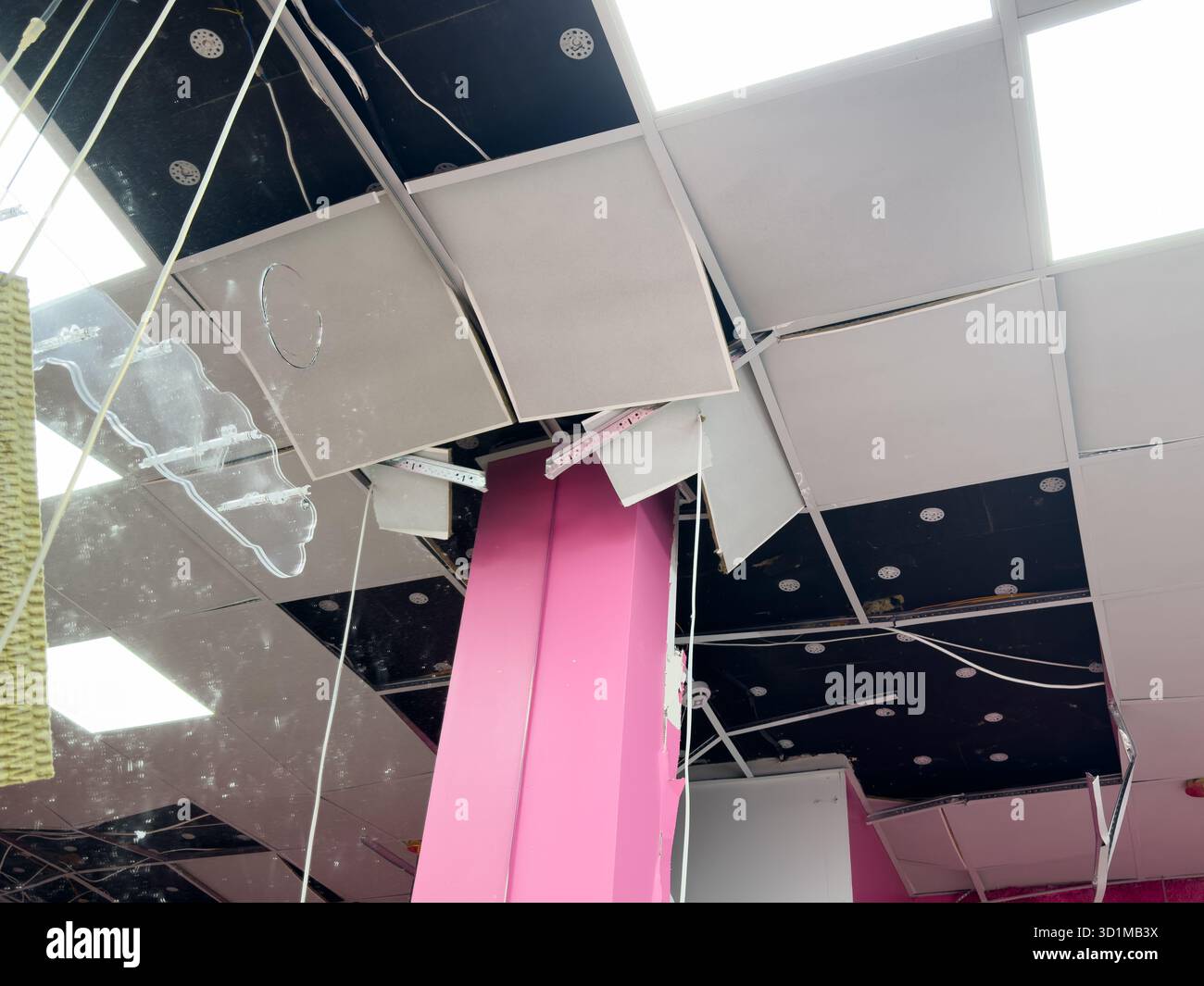 Broken suspended ceiling tiles revealing electrical wiring and ...