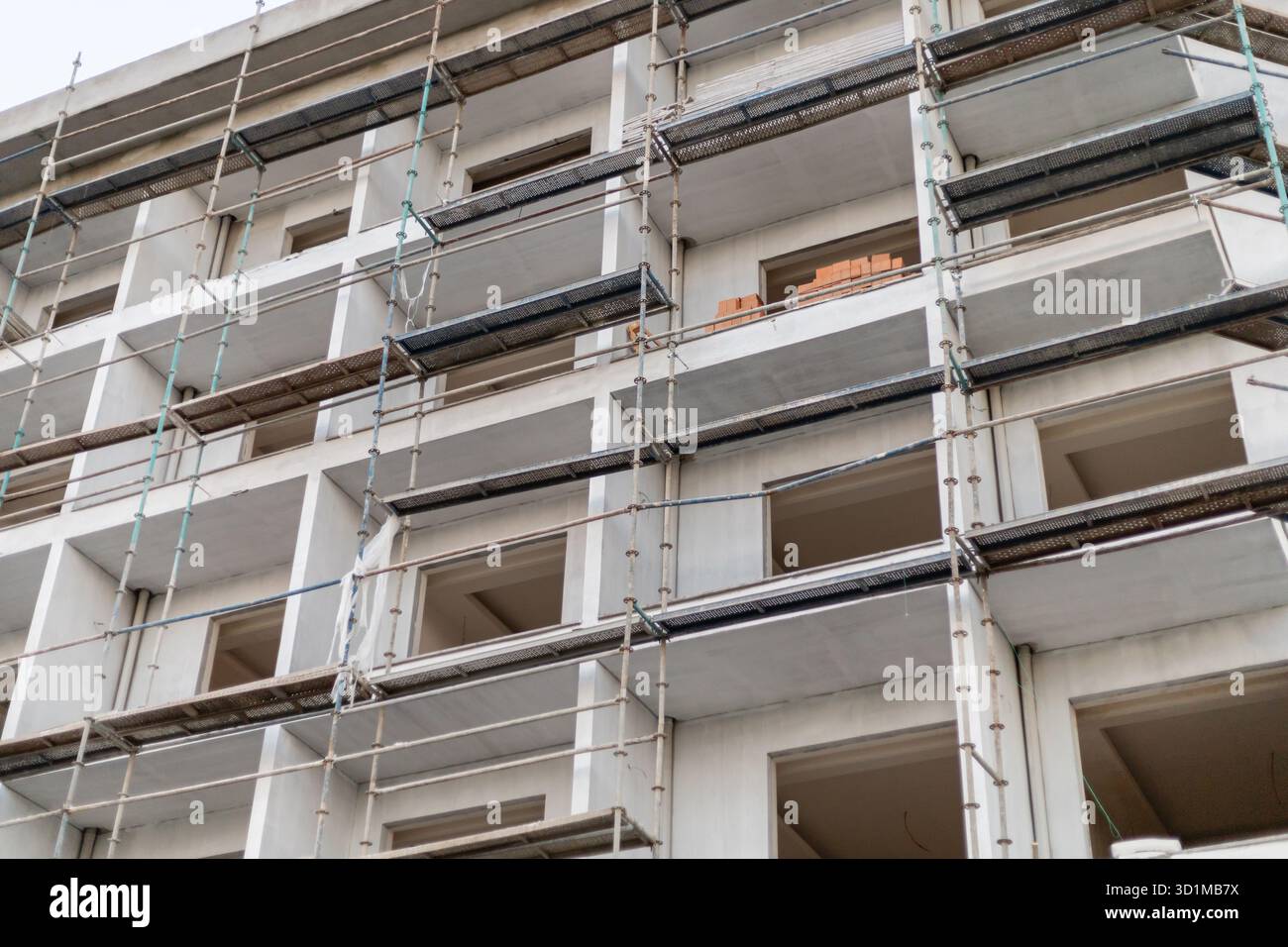 Workers are using scaffolding to access different levels of a multi-story building under ...