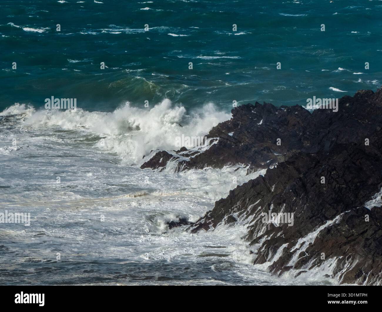 Waves crashing on the rocks below Mizen Head Lighthouse, and sending up ...