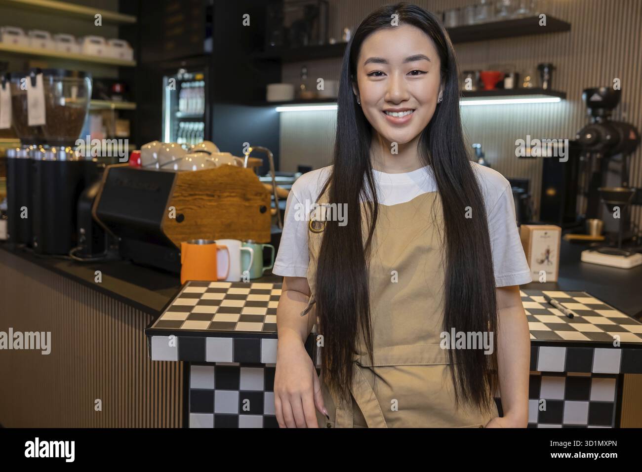 Smiling cute long-haired young Asian female employee leaning on the ...