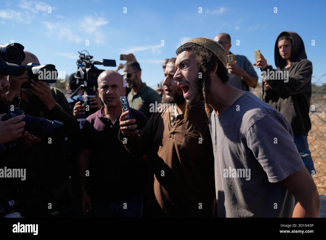 Israeli settlers take pictures of foreign activists and farmers while ...