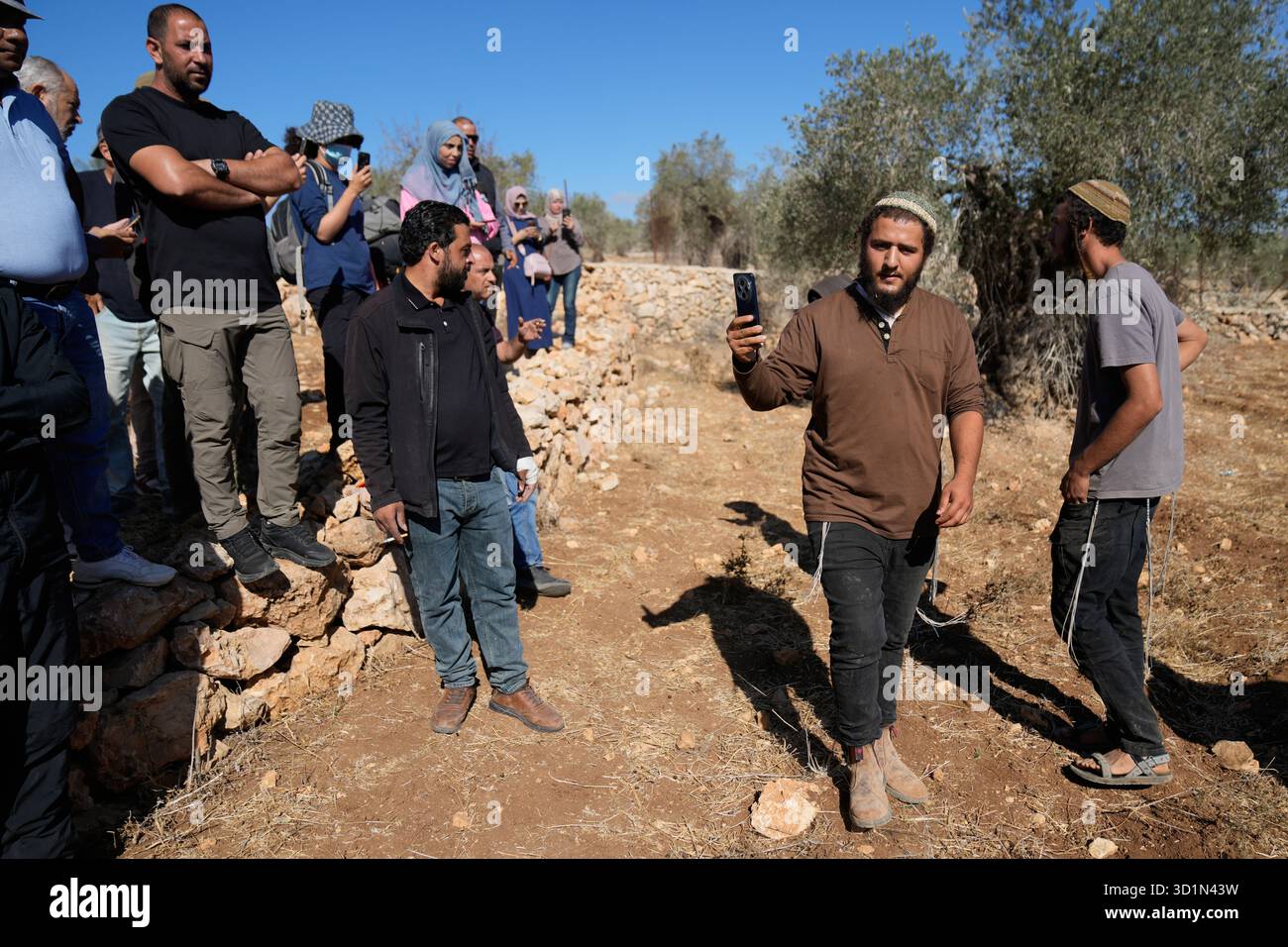 Israeli settlers take pictures of foreign activists and farmers as they ...