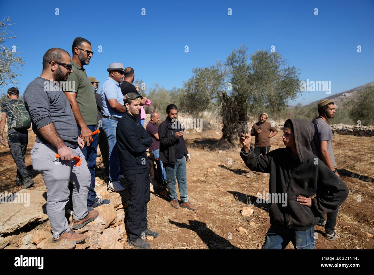 Israeli settlers take pictures of foreign activists and farmers as they ...