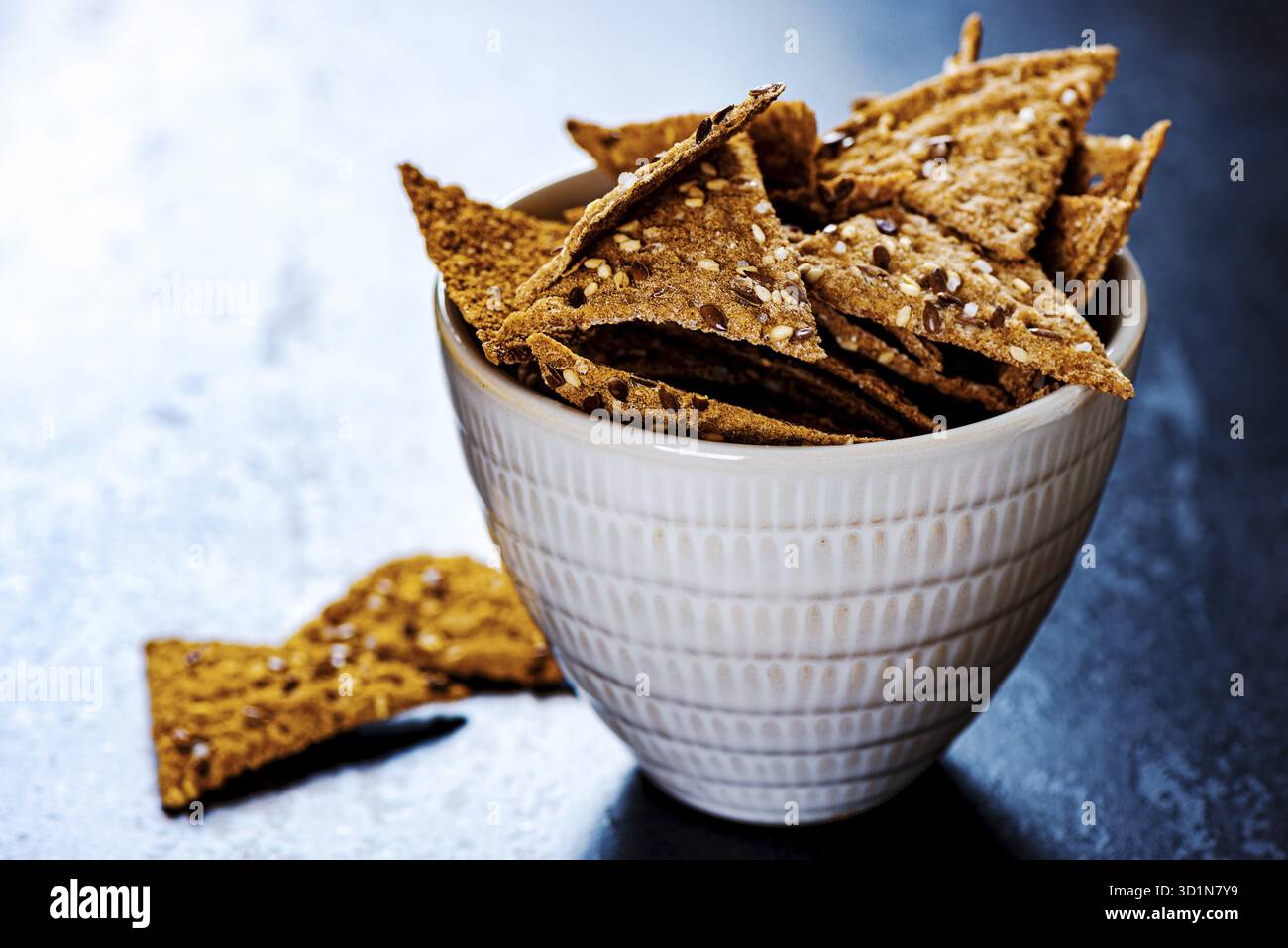 Sesame triangular crispy chips in bowl Stock Photo - Alamy