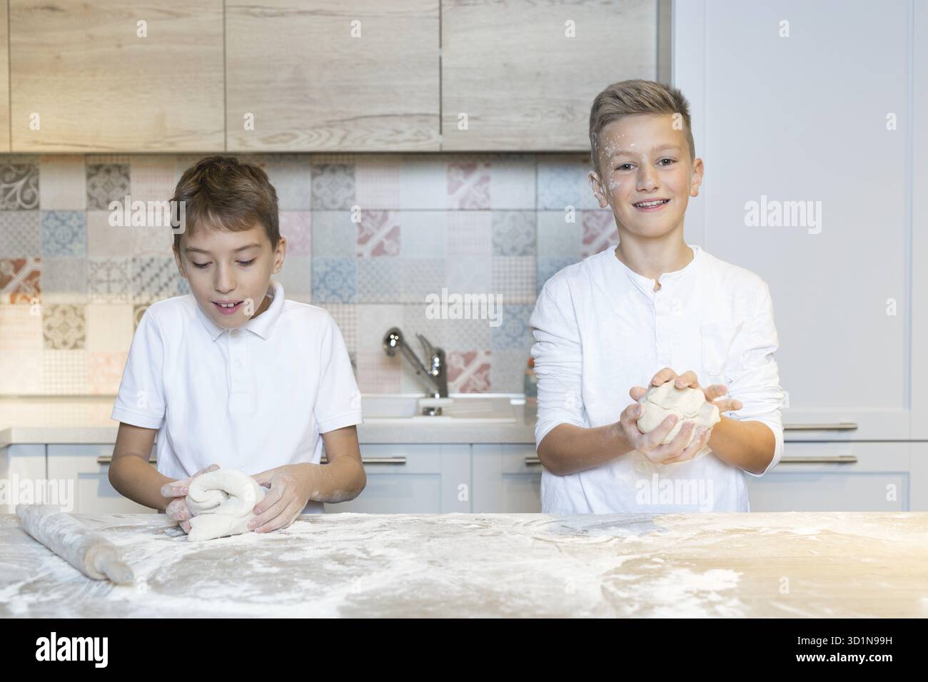 Two children having fun baking in the kitchen, Two brothers playing in ...