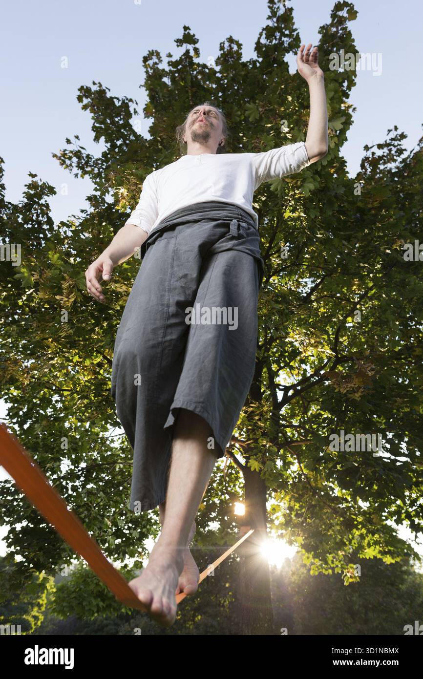 Guy practising slack line in the city park Stock Photo - Alamy