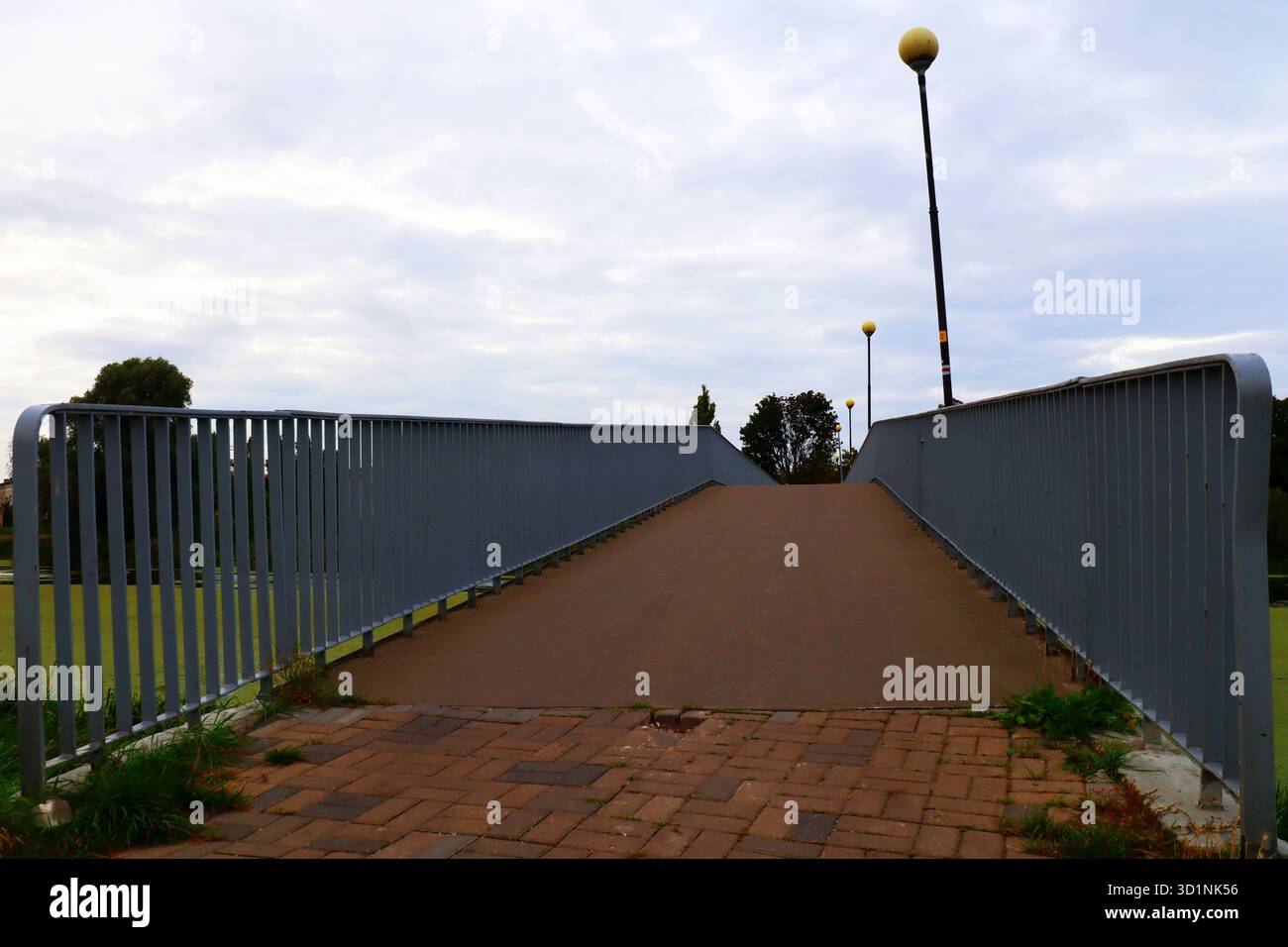 Pedestrian bridge ramp with metal railings and streetlights under an ...