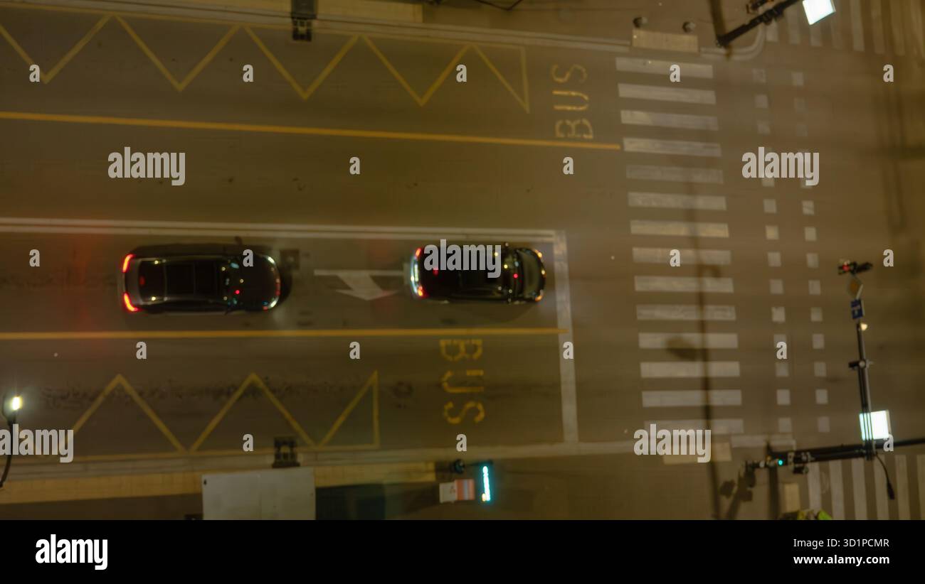 Aerial night view of city street with two cars driving between bus ...