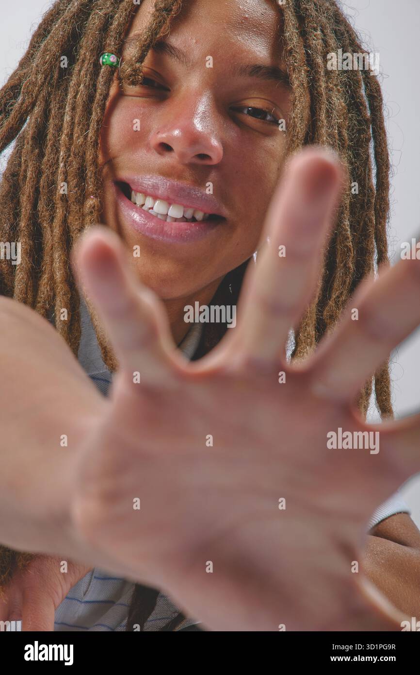 Joyful person with dreadlocks reaching hand forward looking directly at ...