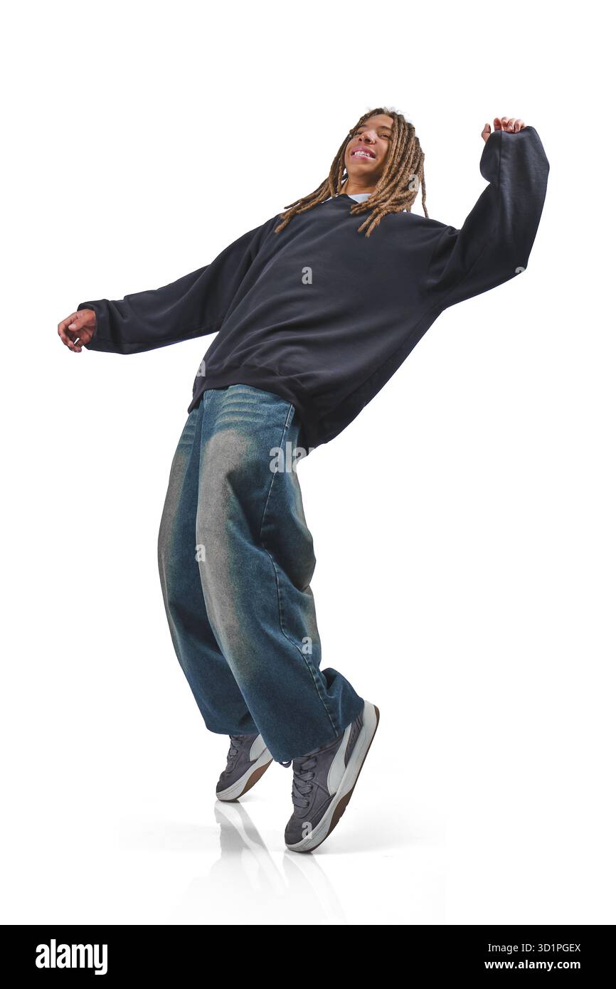 Young man with dreadlocks dancing in hip hop attire, making a stop ...