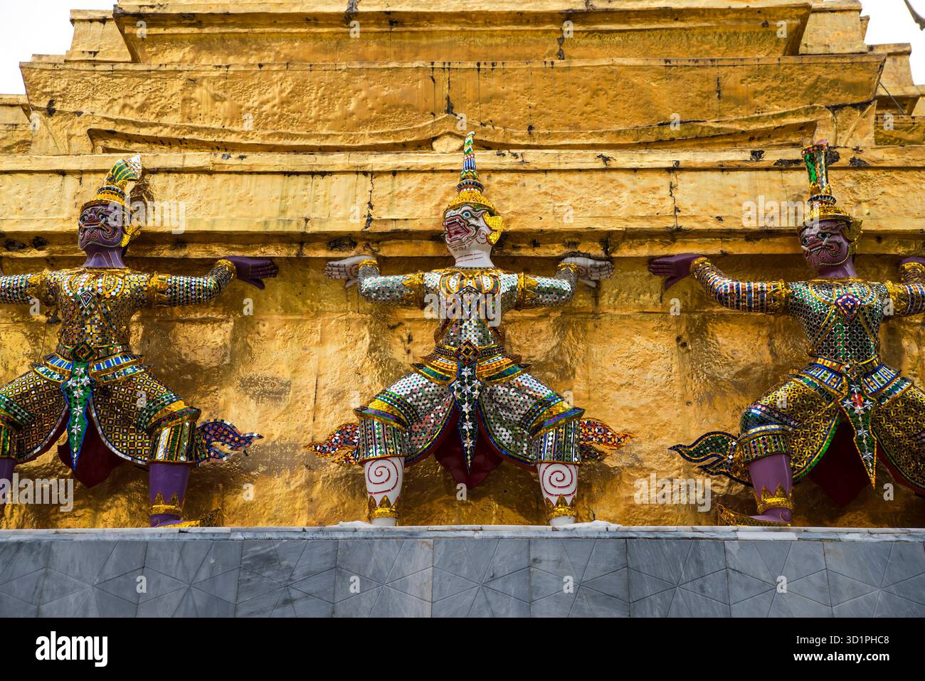 Three statues of men in gold and purple standing on a building. The ...
