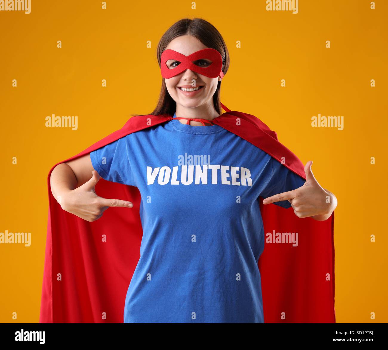 Woman in superhero costume pointing at word Volunteer on her shirt ...