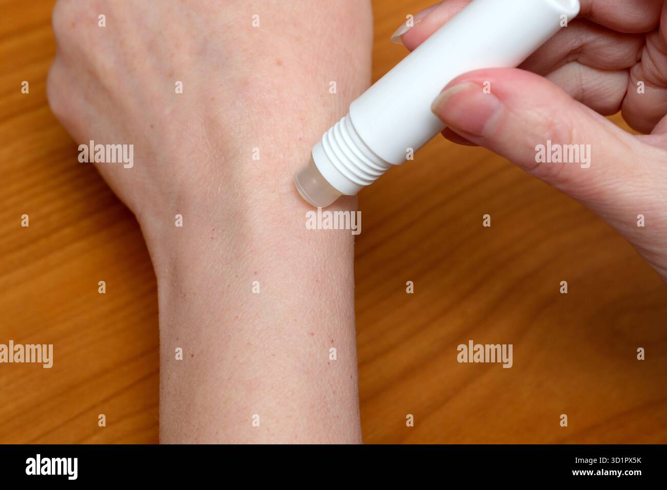 A person applies a roll-on treatment to their wrist for soothing relief ...