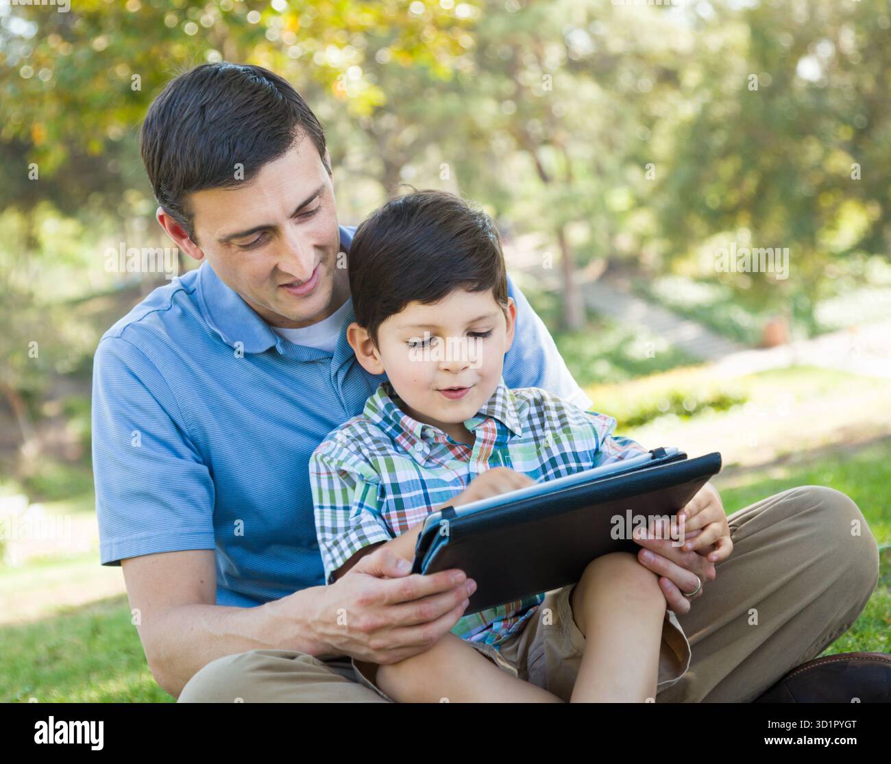 Happy Father and Son Playing on a Computer Tablet Outside Stock Photo ...