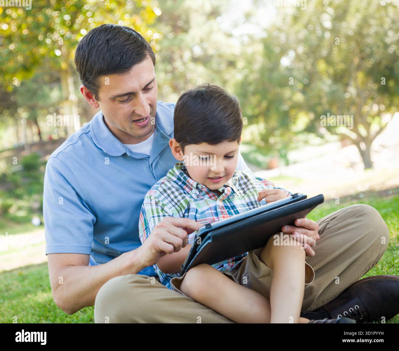 Happy Father and Son Playing on a Computer Tablet Outside Stock Photo ...