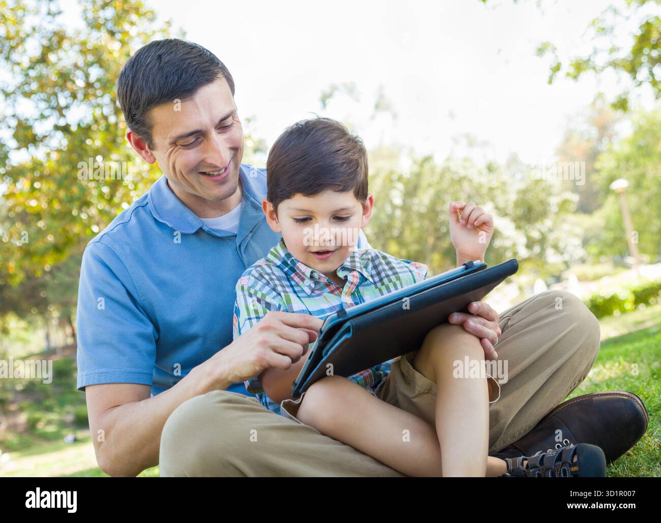 Happy Father and Son Playing on a Computer Tablet Outside Stock Photo ...