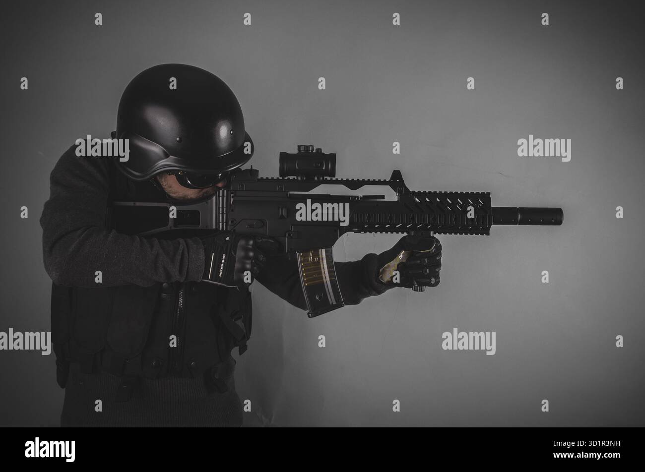 Sniper, airsoft player with gun, helmet and bulletproof vest on gray ...