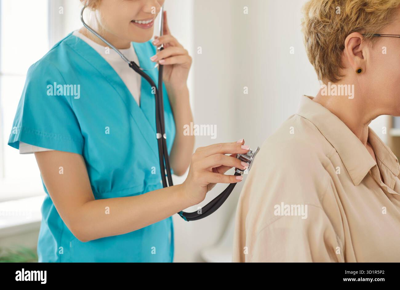 Nurse using stethoscope on back of senior patient to examine during ...