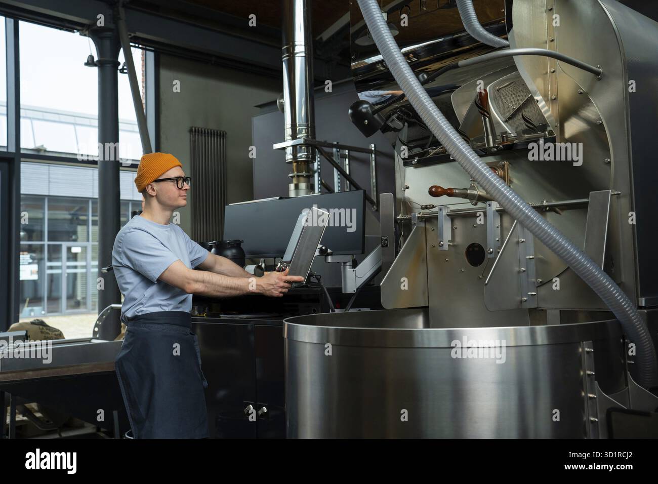 Modern coffee roasting factory, man operating process of creating ...