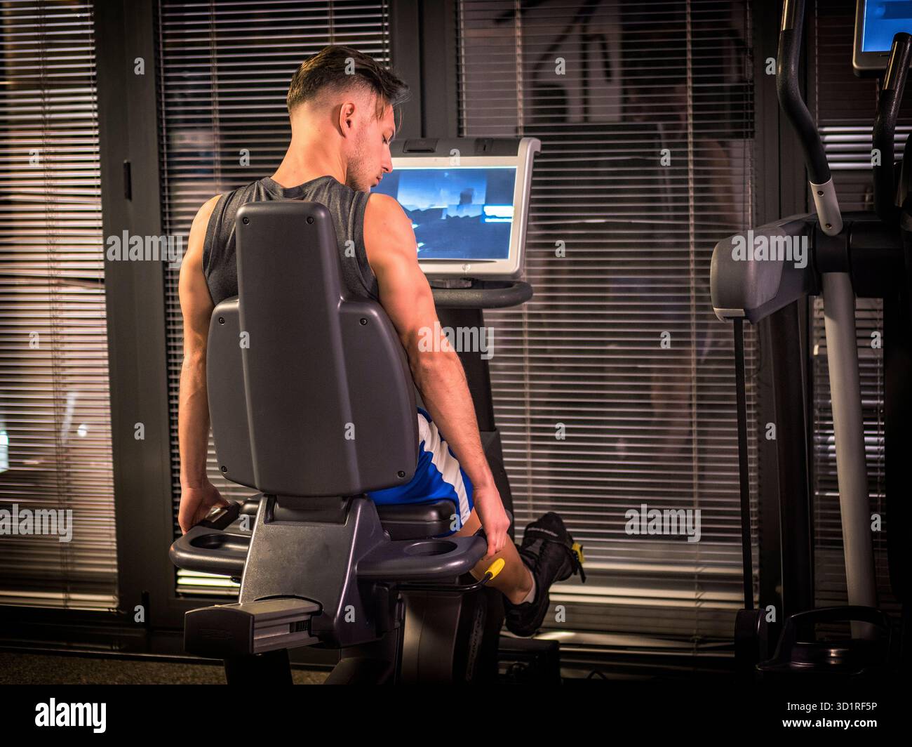 Muscular young man, training legs on gym machine Stock Photo - Alamy