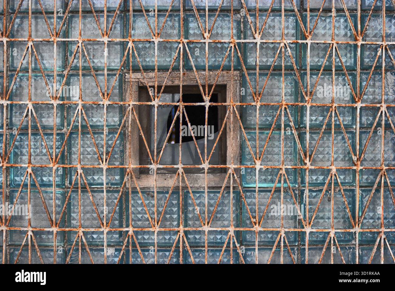 Glass block of the old window covered with rusty grid for construction ...