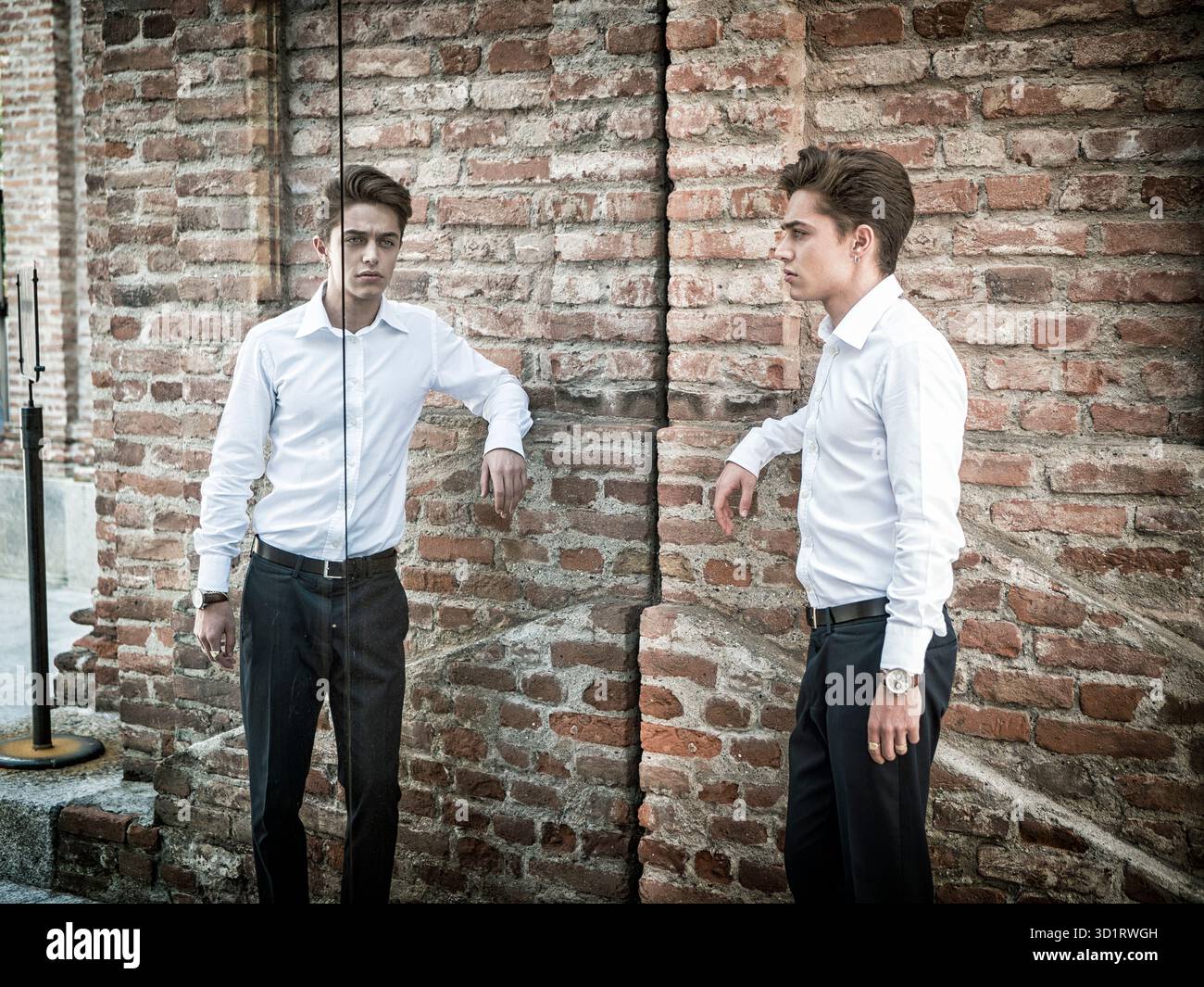 Attractive young man standing against brick wall Stock Photo - Alamy