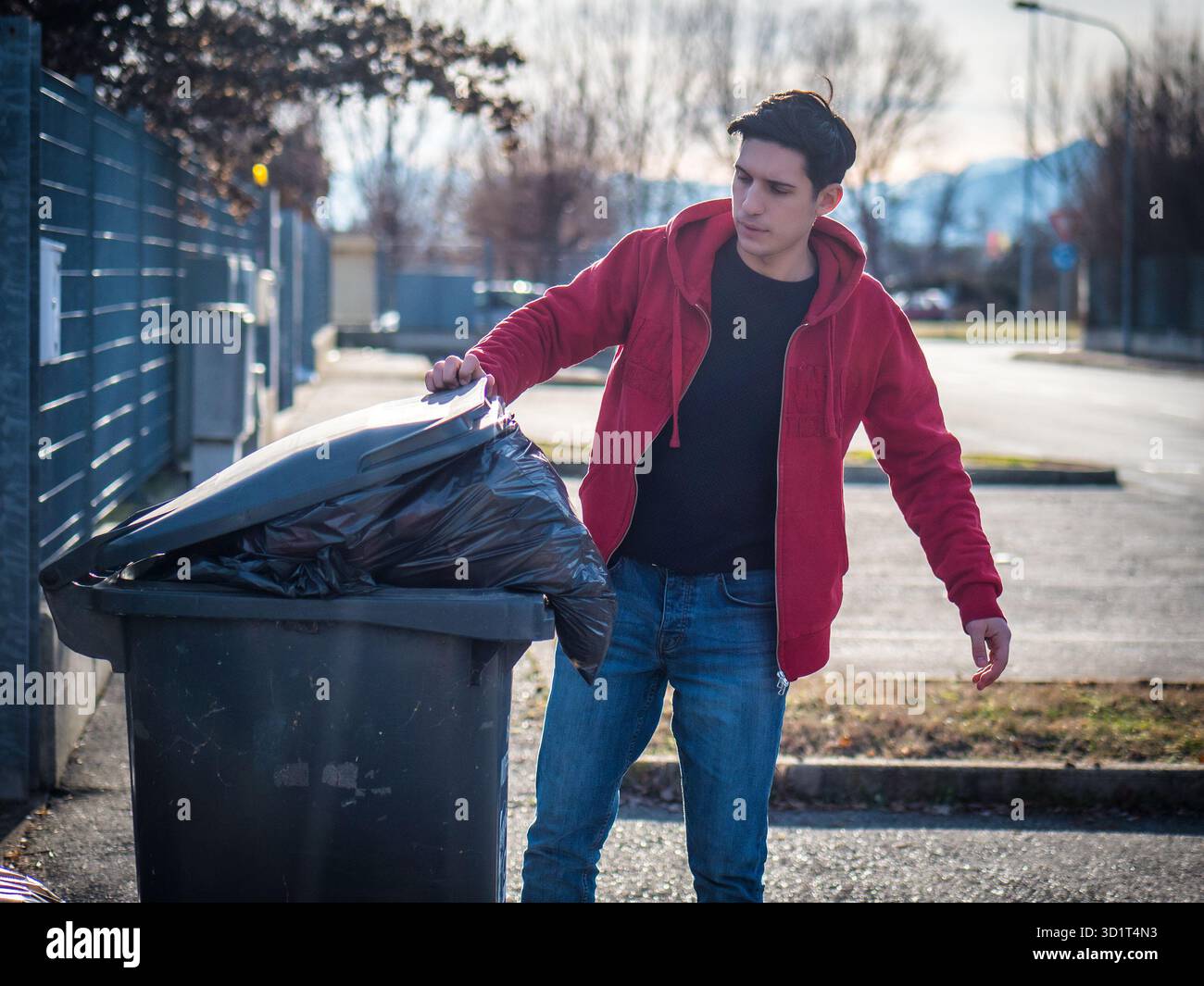Attractive young man putting out rubbish standing Stock Photo - Alamy