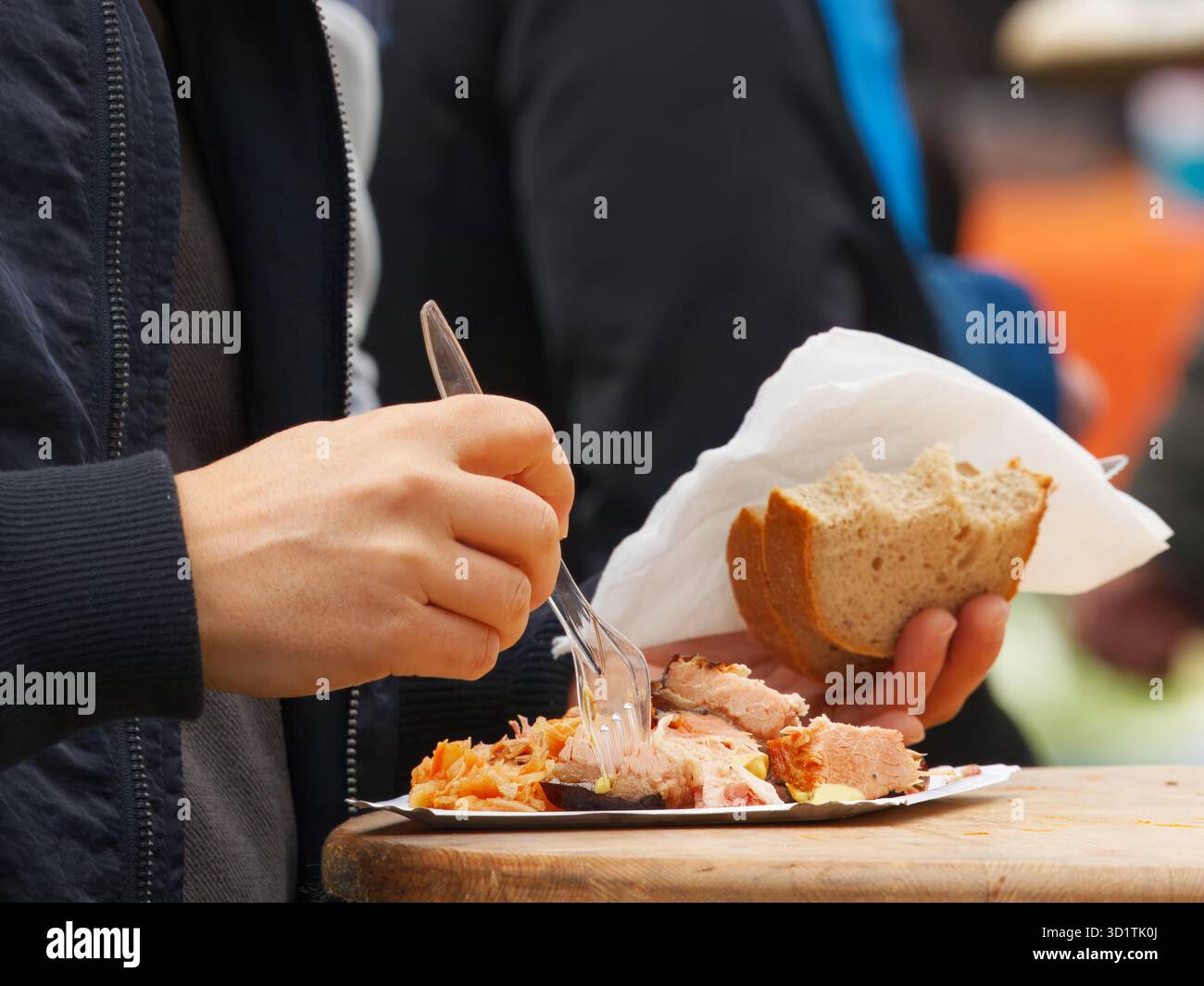 Close-up of a person eating a traditional pork dish with bread at a ...