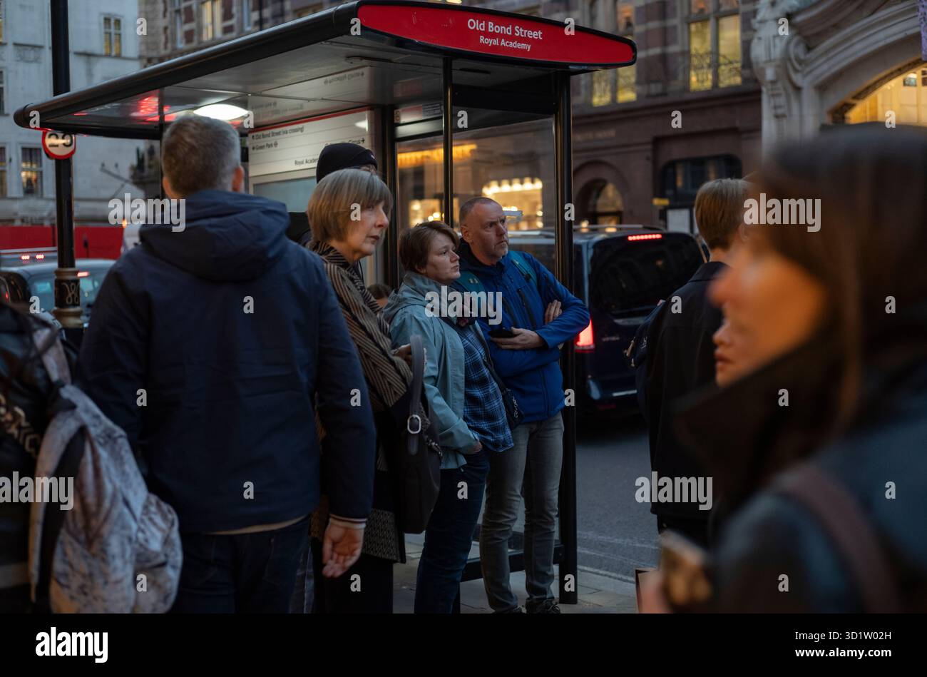 London commuters queuing at a bus shelter waiting to travel home during ...