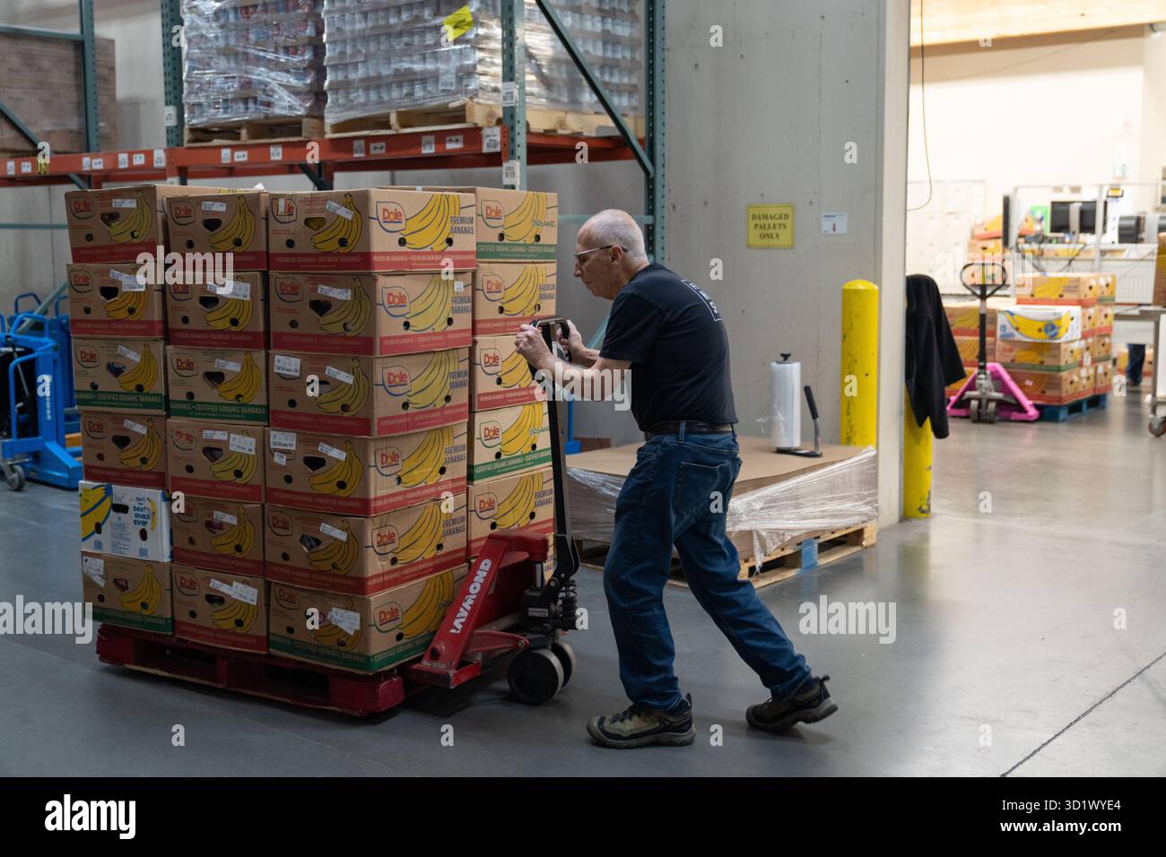 A volunteer moves a pallet filled with items for distribution at the ...