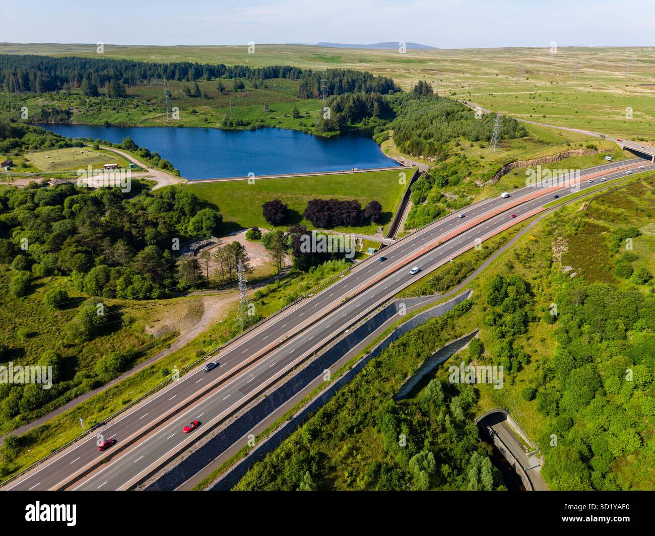 Cars driving on a multi-lane highway through the green hills and ...