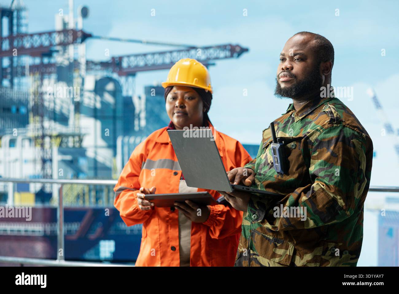 Army soldier protecting offshore rig next to employee monitoring ...