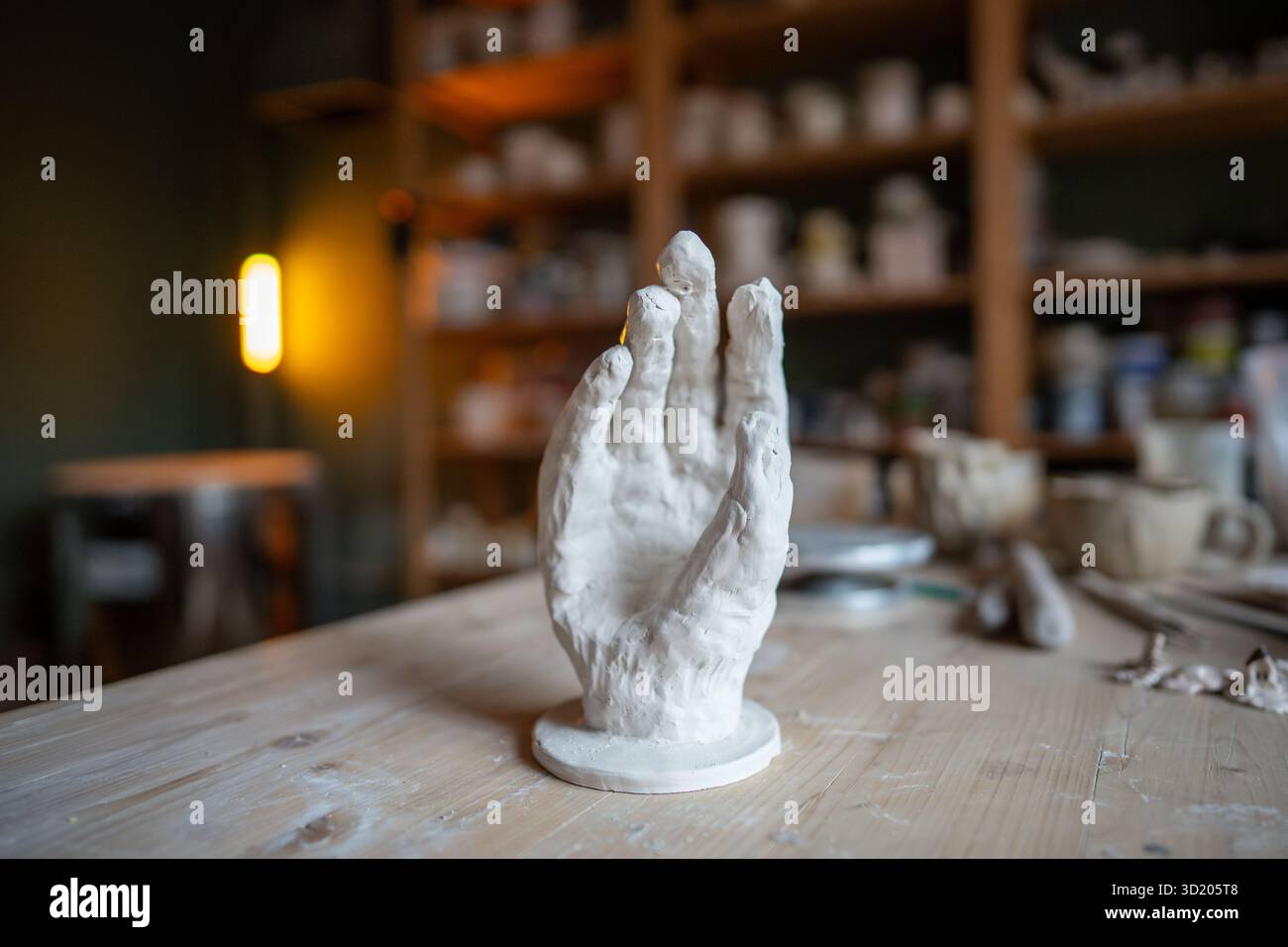 Pottery workshop with clay hand palm on table, bespoke piece of modern ...