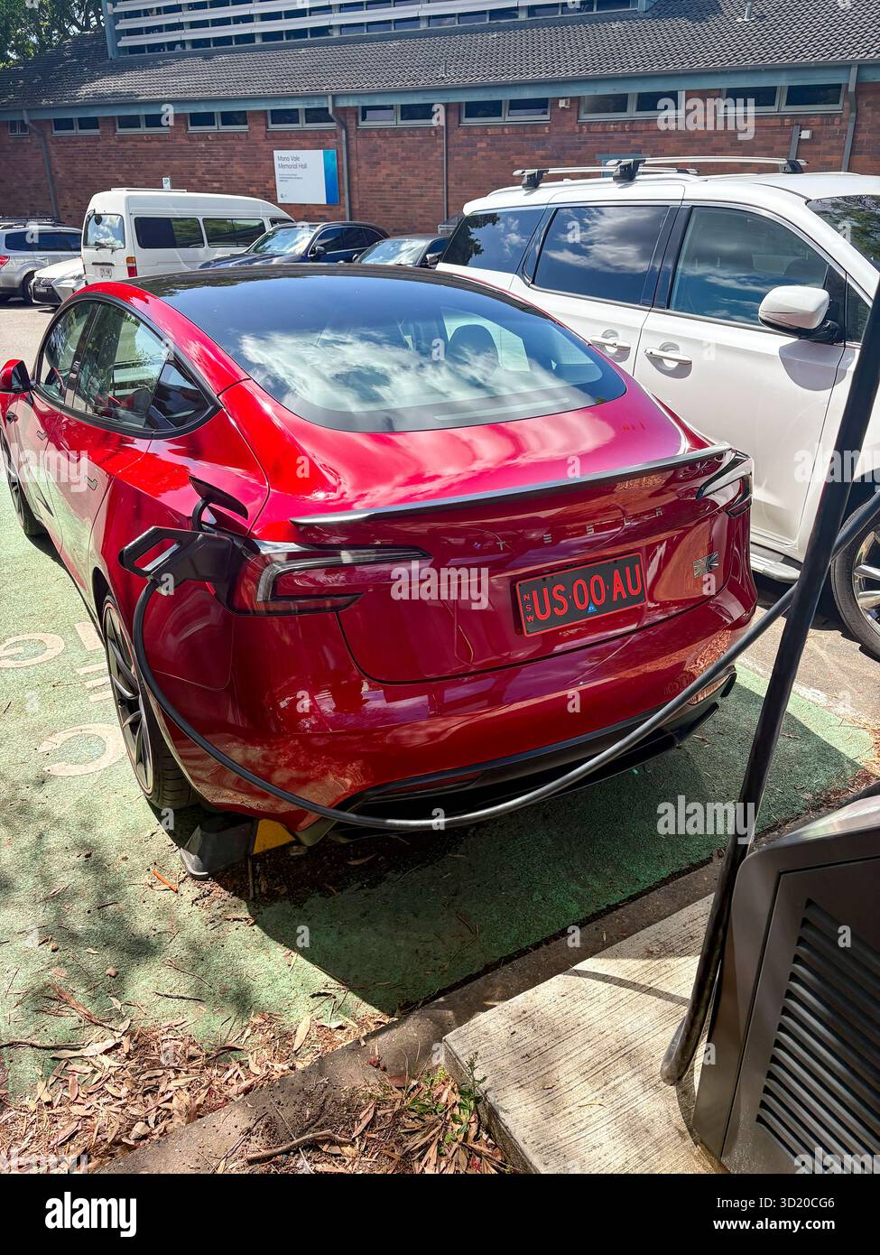 2024 red Tesla Model 3 electric vehicle being charged on a public Jolt ...