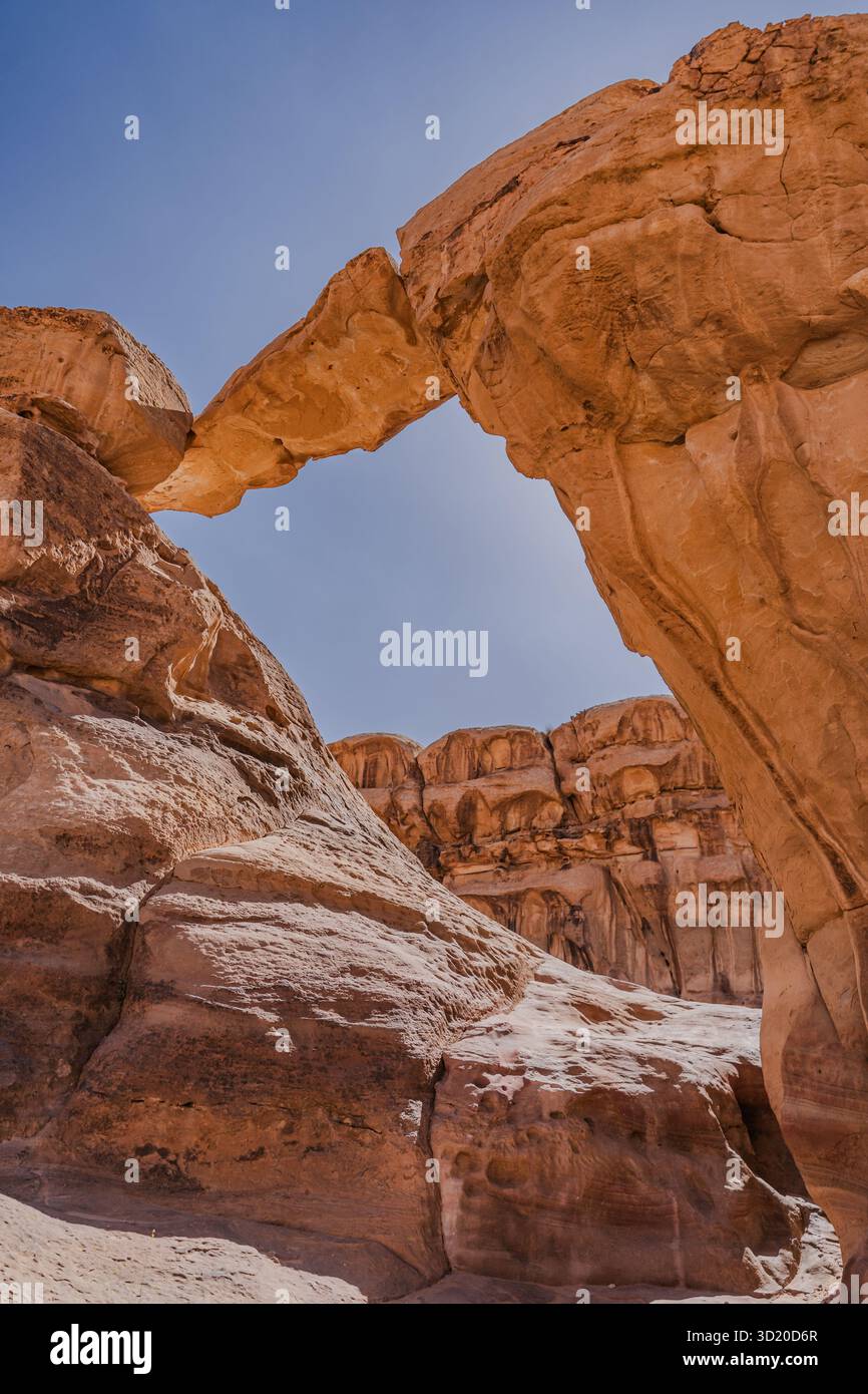 Natural rock arch formation illuminated by midday light in the desert ...